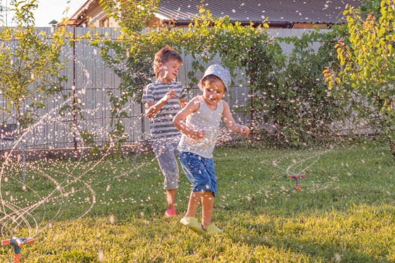 Summer activities. Children playing outdoor with automatic plant ...